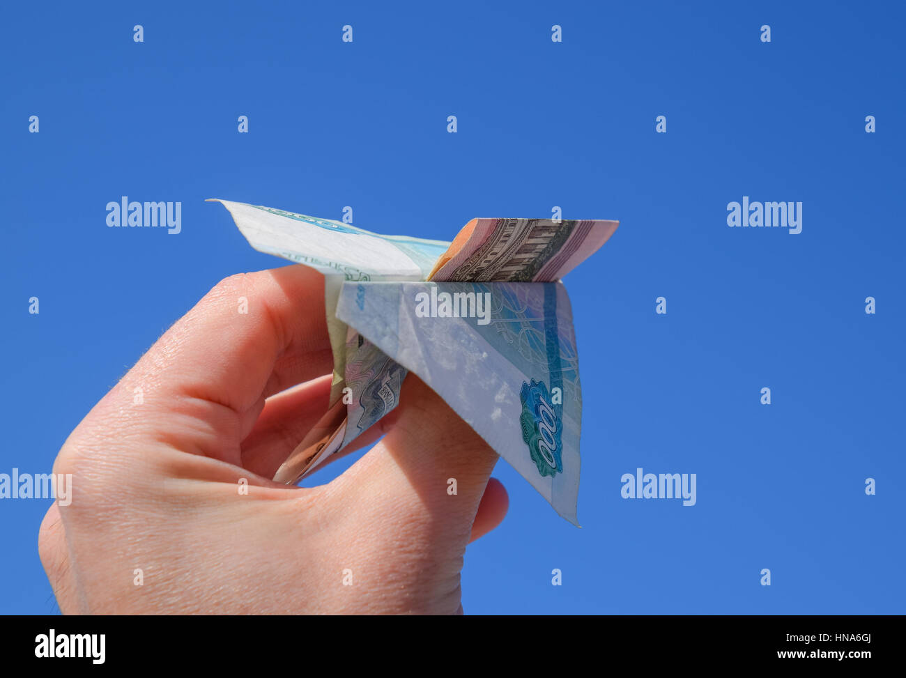 Denominations of Russian money, folded in the airplane against the blue ...