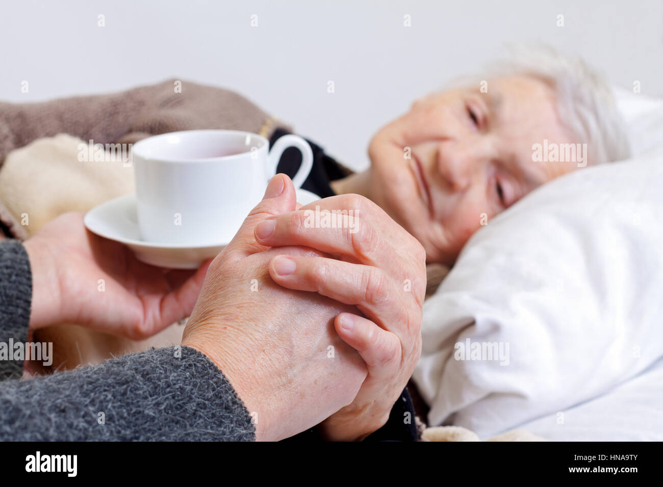 Picture of a woman hand giving tea to an elderly woman Stock Photo - Alamy