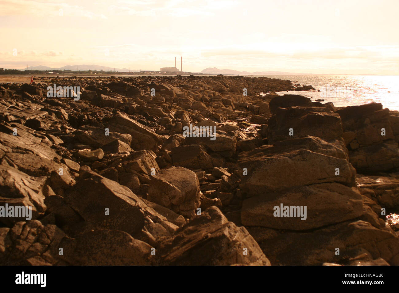 The rocky beach at Longniddry Bents with Cockenzie power station in the ...