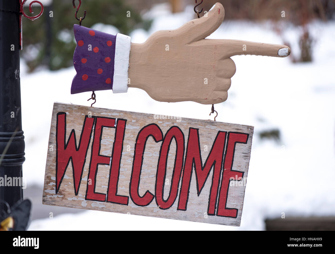 A welcome sign hangs below a hand pointing the direction Stock Photo ...