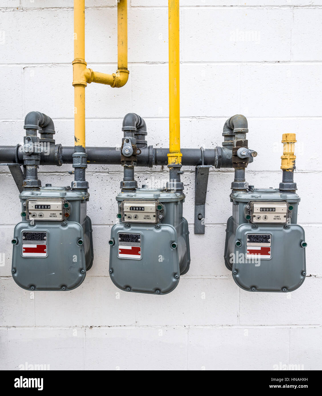 A horizontal image of natural gas meters hanging outside on a white ...