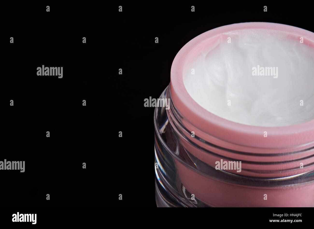 face cream in pink jar isolated on black background with copy space ...