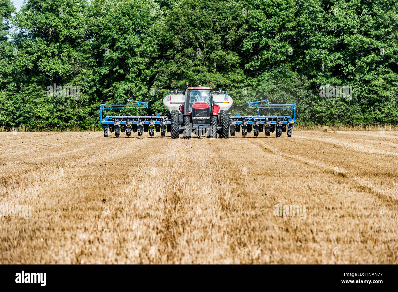 A planter moves through a large field planting soy beans on a farm ...