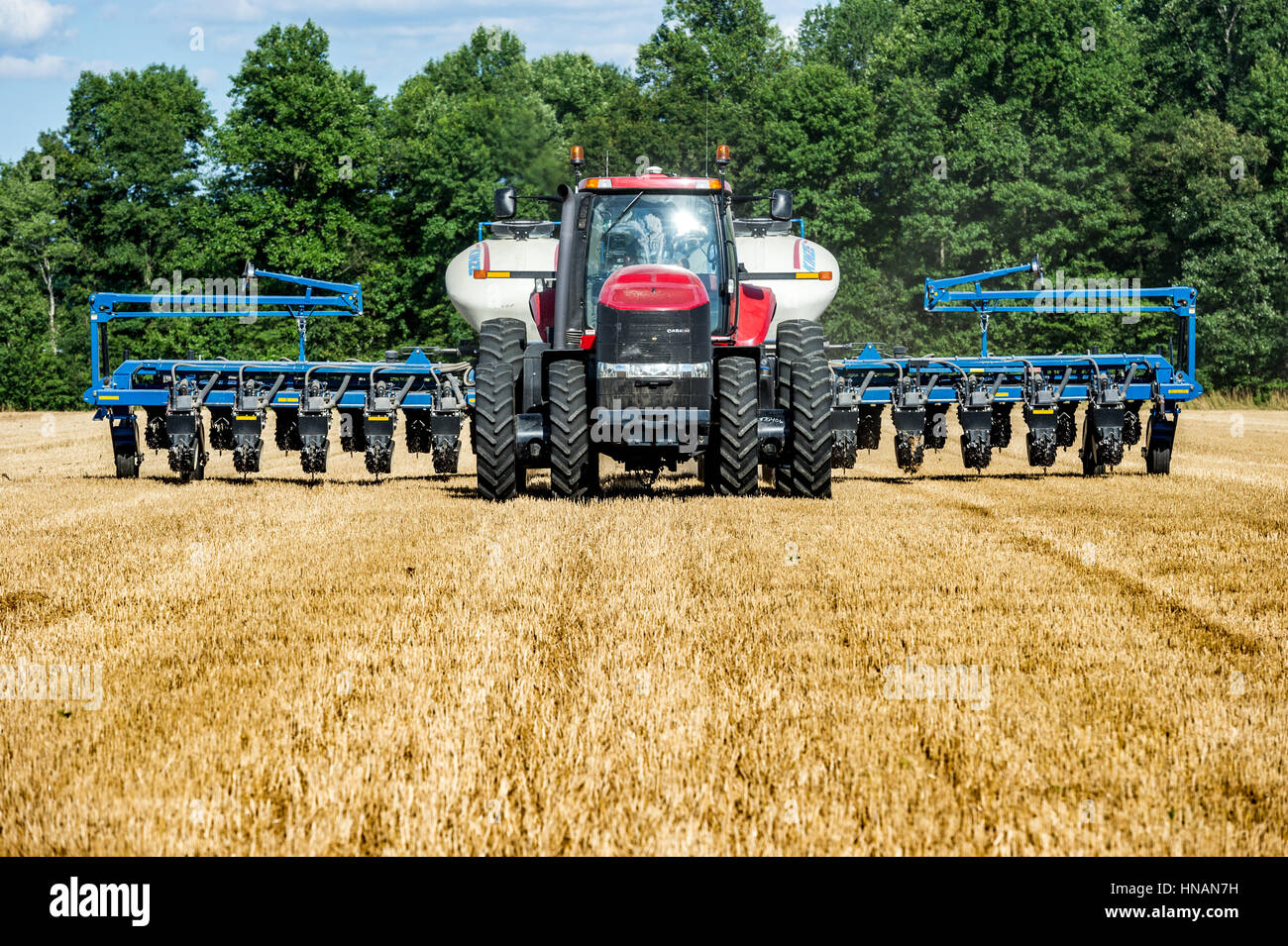 A planter moves through a large field planting soy beans on a farm ...