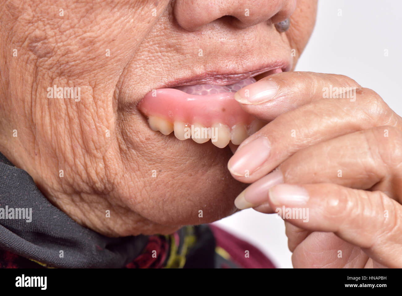 senior woman putting false tooth into her mouth Stock Photo - Alamy