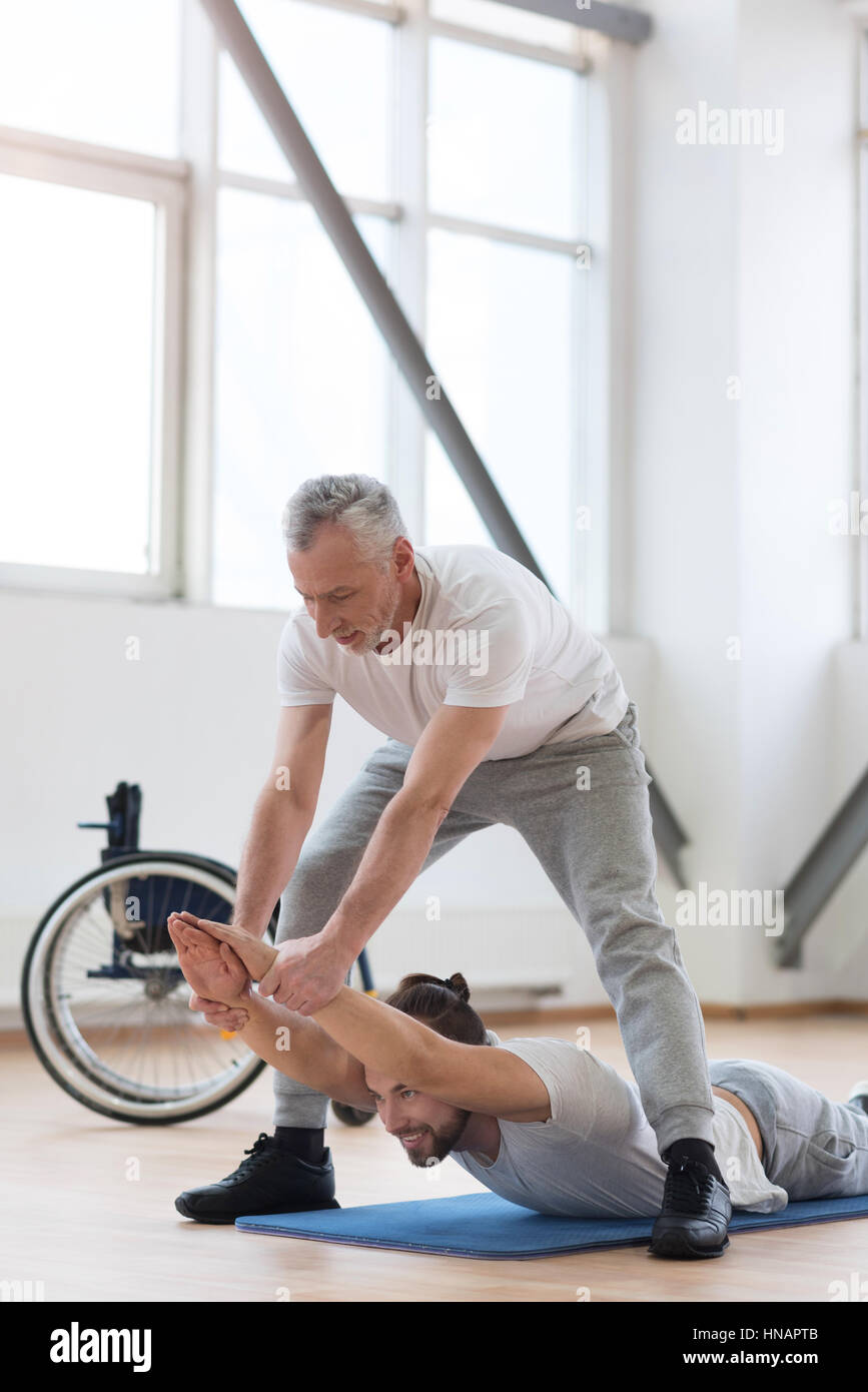 Experienced physical therapist working out with disabled in the gym ...