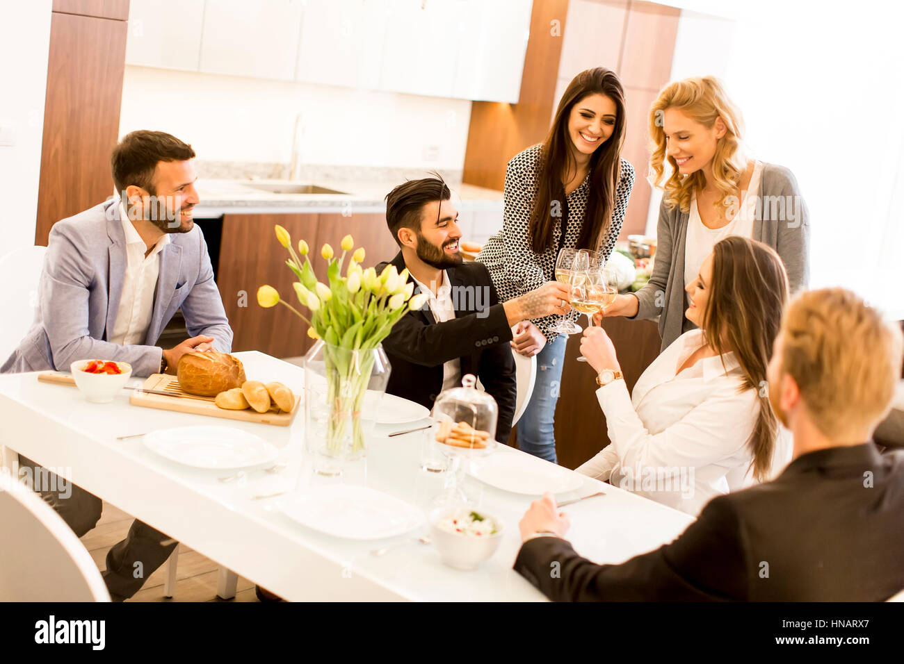 Friends interacting while having a meal at dining table and toast with ...