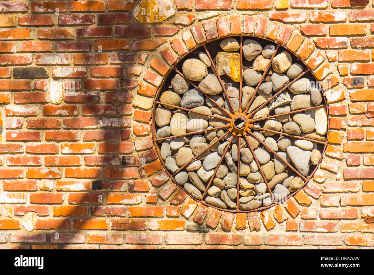 Used Brick Wall With River Rock Behind Spokes Of Wheel Stock Photo - Alamy