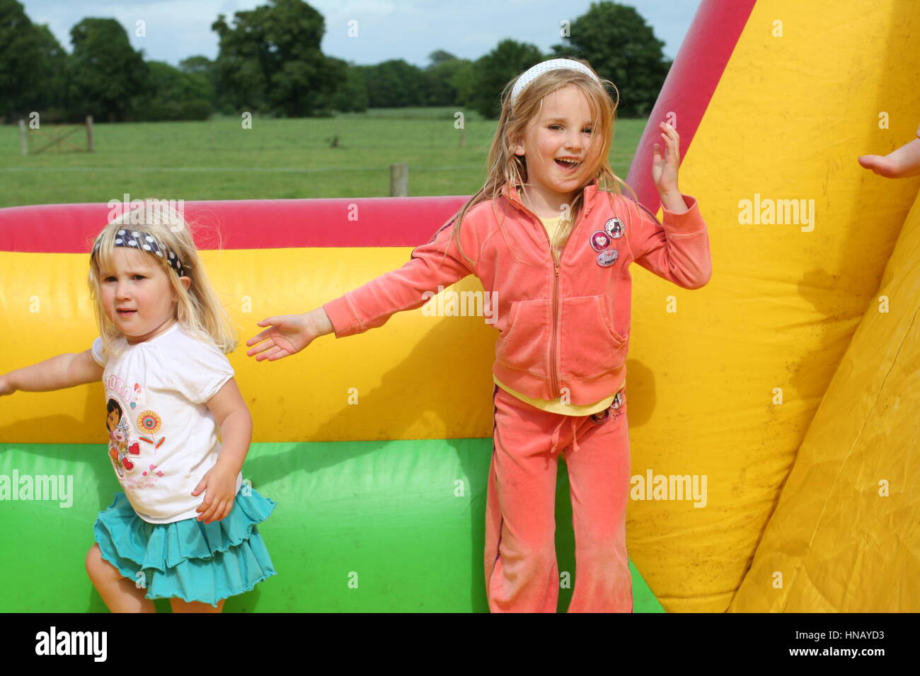 Blonde Children kids having fun bouncing jumping on a bouncy castle ...