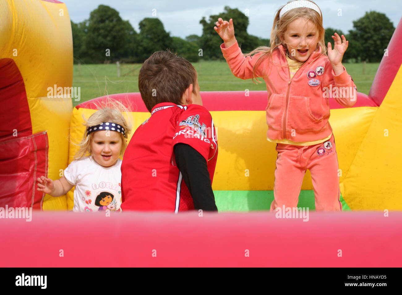 Blonde Children kids having fun bouncing jumping on a bouncy castle ...