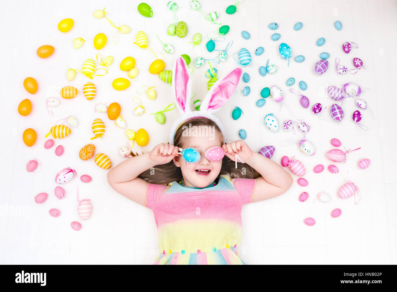 Funny little girl with bunny ears having fun on Easter egg hunt. Child ...
