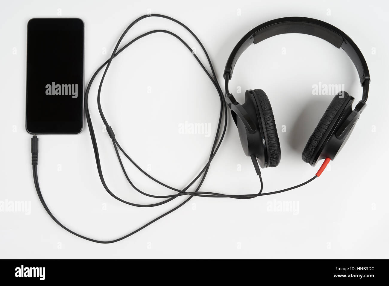 Closed back stereo headphones connected to smart phone on white ...