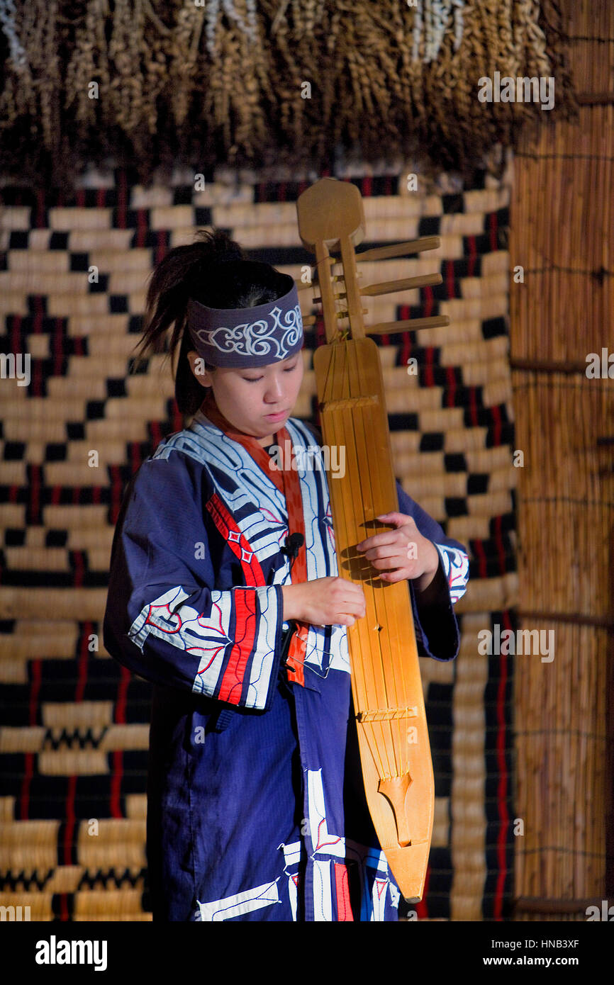 Ainu woman playing a traditional instrument in Ainu village museum ...