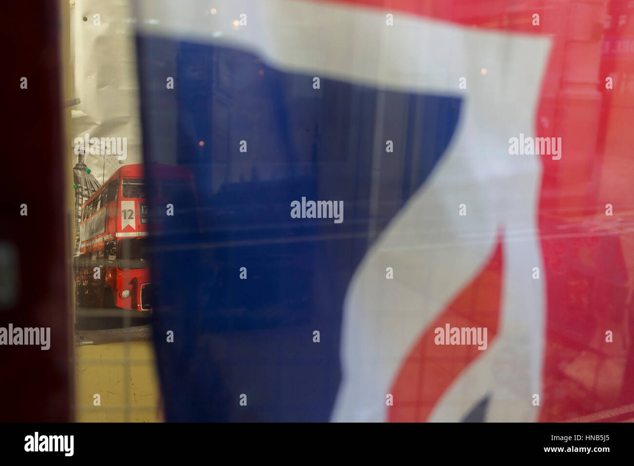 A detail of a red London bus with London landmarks peeping behind a ...