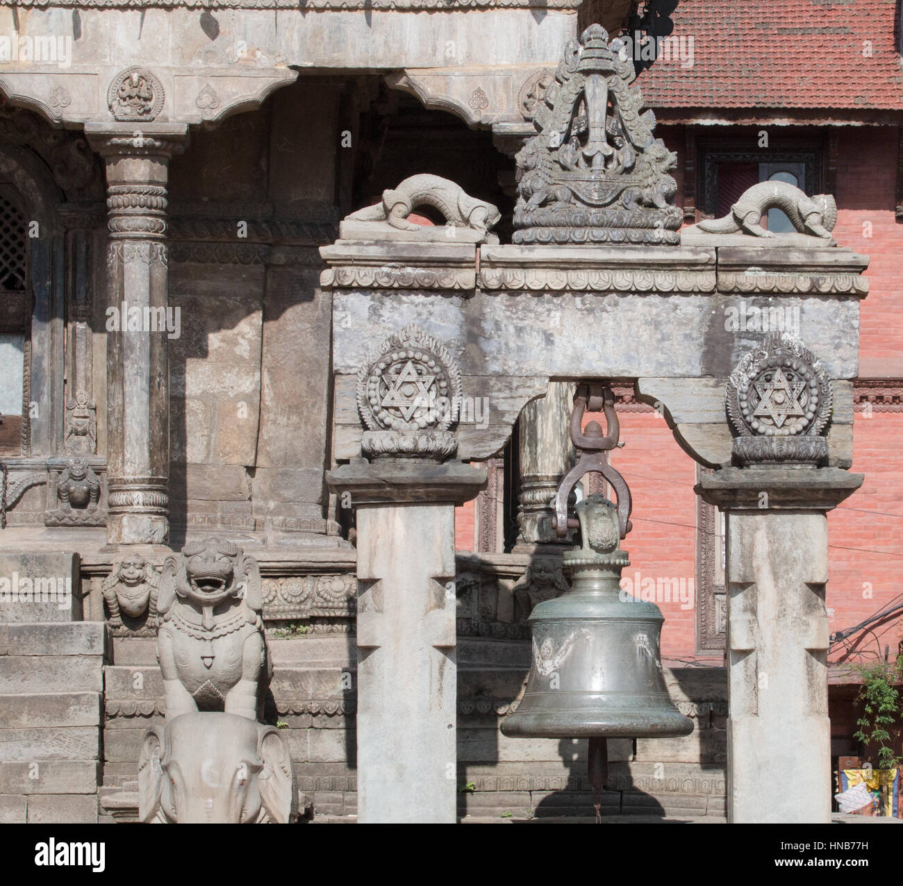 Big brass bell on a carved wooden post outside a Hindu temple in Patan ...