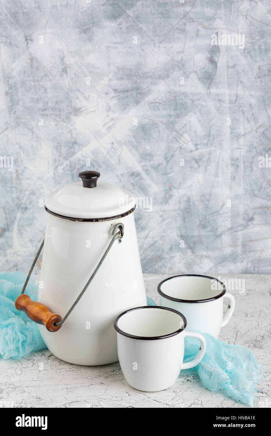 Two white cups and white enameled cans on light background Stock Photo ...