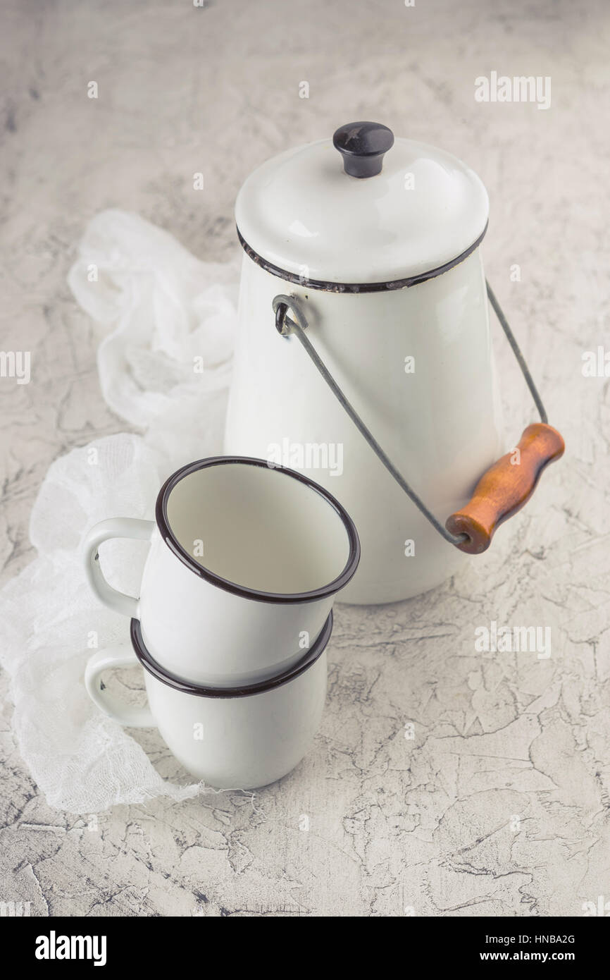 Two white cups and white enameled cans on light background Stock Photo ...