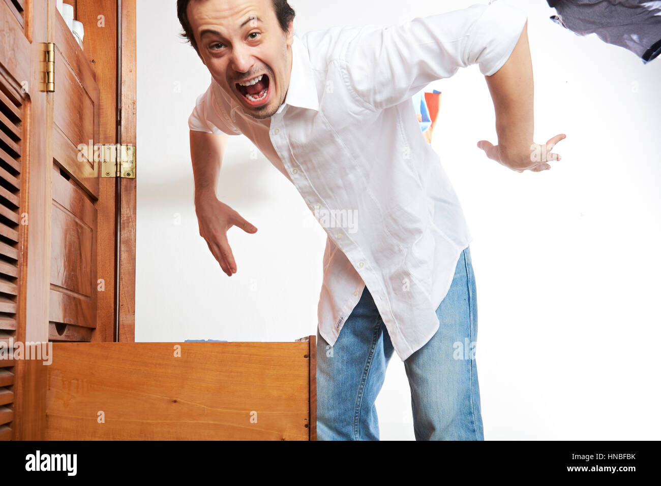 angry young man throwing clothes from wardrobe isolated on white Stock ...