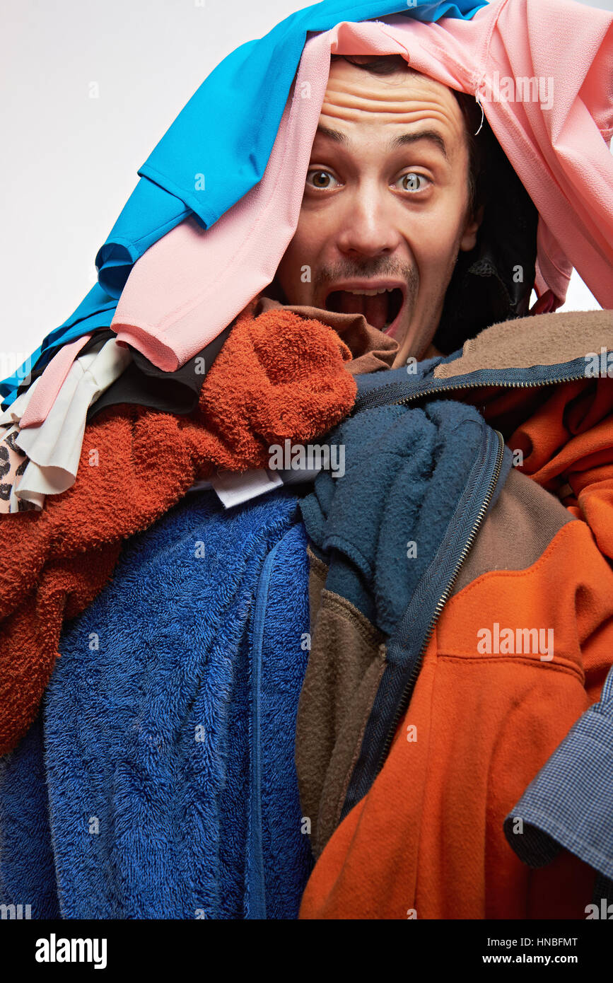 young man look out from messy colourful clothes Stock Photo - Alamy