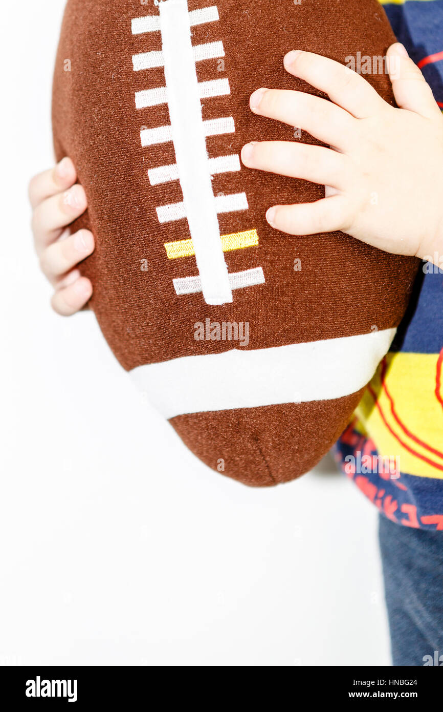 brown rugby ball toy for children in boys hands with white background ...