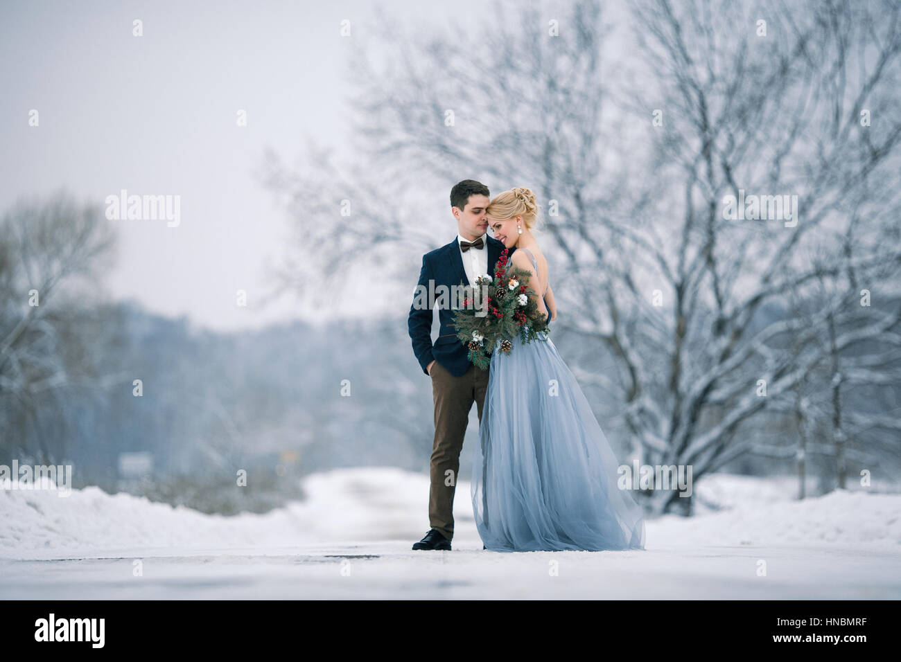 Bride and groom among snowy landscape. Bride and groom are standing and ...
