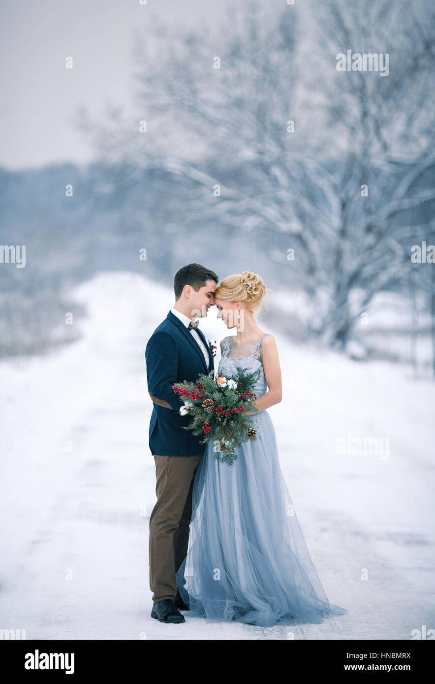 Bride and groom among snowy landscape. Bride and groom are standing and ...