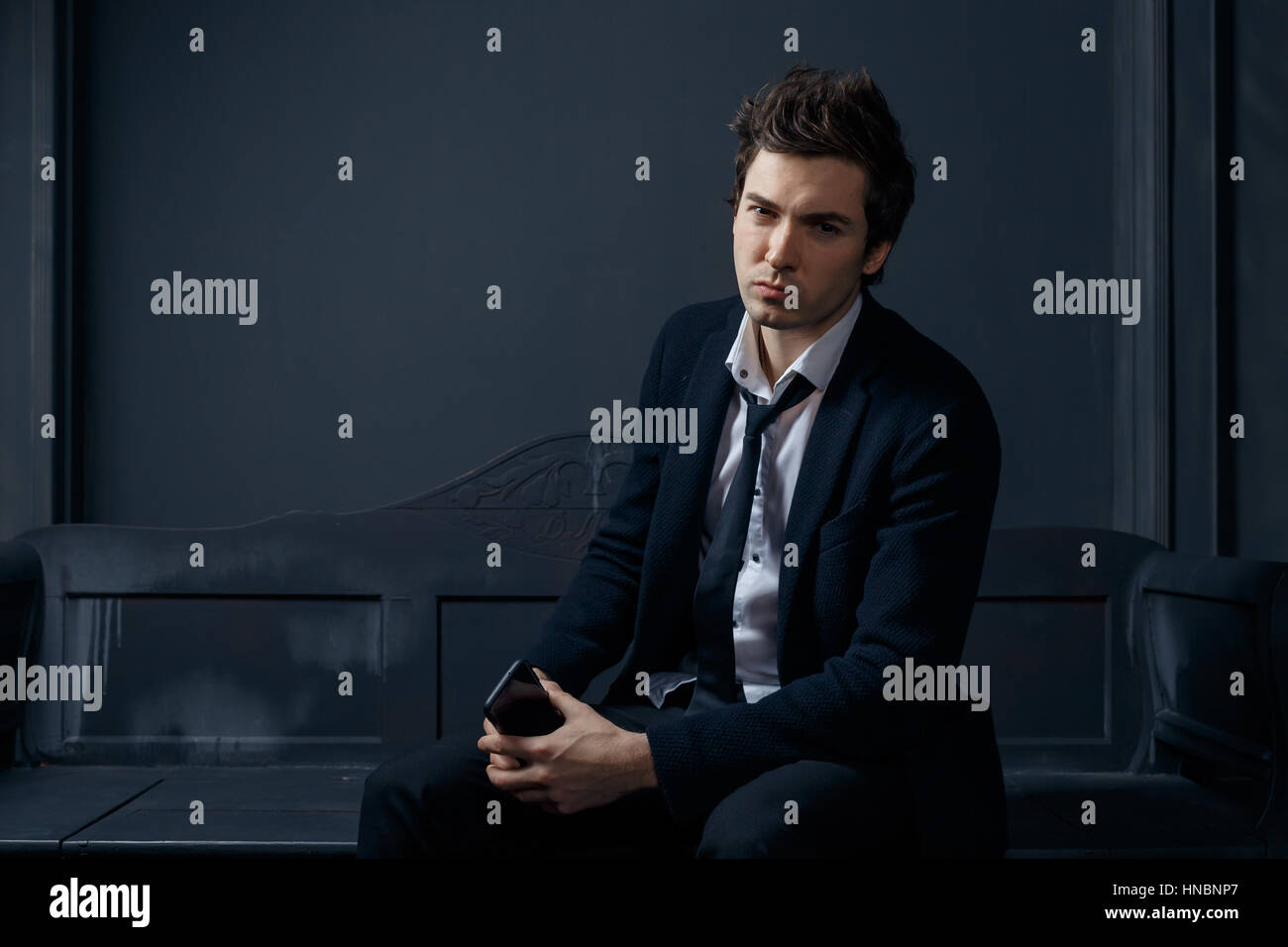 Man in the black suit in dark room. Dark room in loft style Stock Photo ...