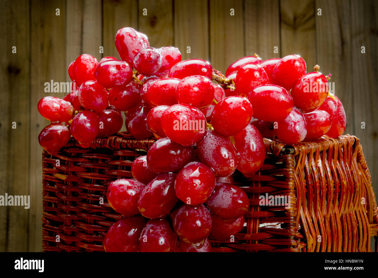Wet red grapes in a wicker basket Stock Photo - Alamy