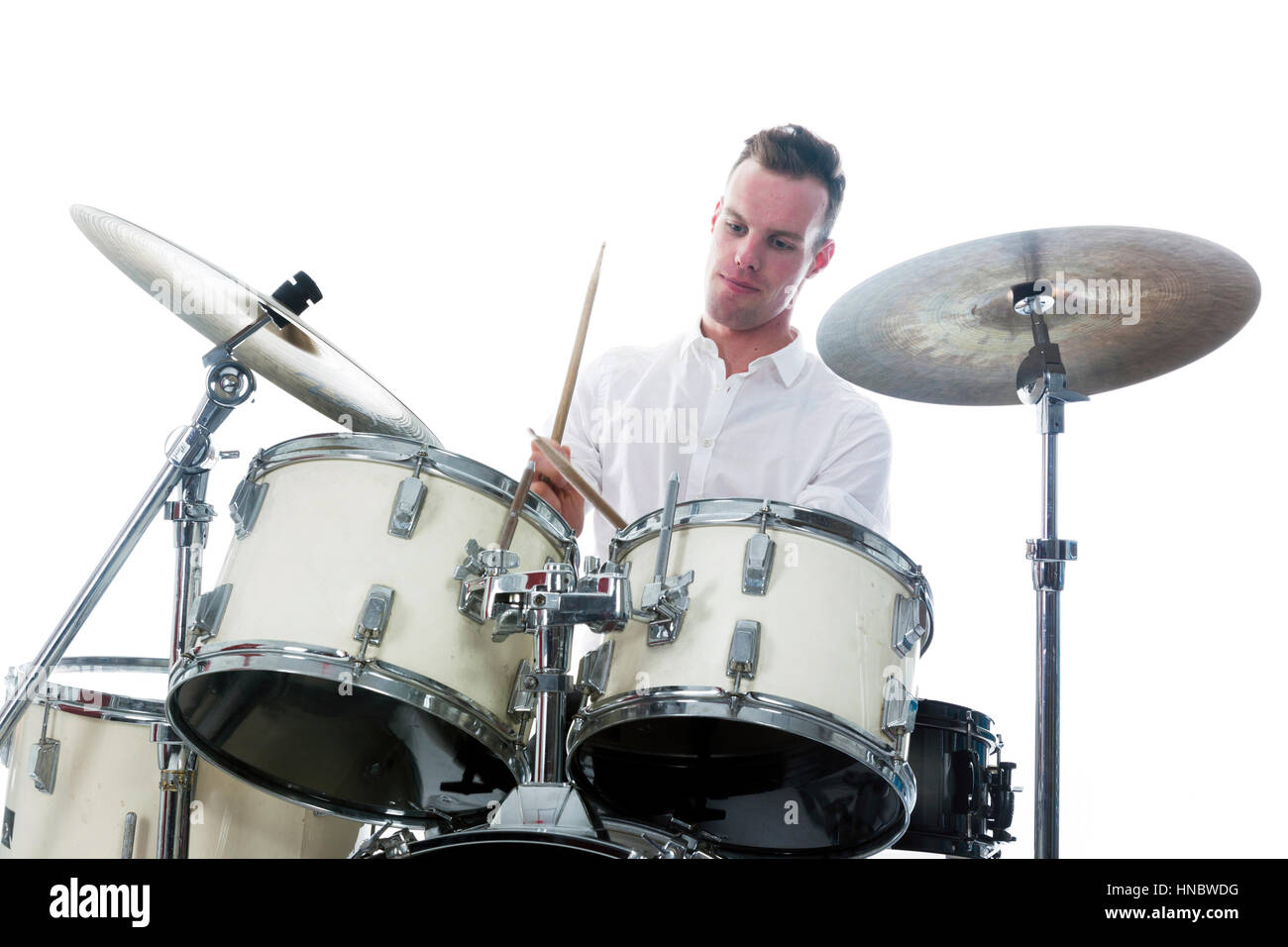 white drummer behind drum set wears white shirt and plays the drums in ...