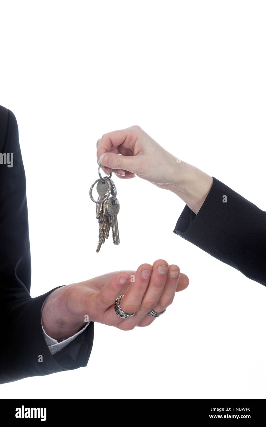 closeup of one hand with key ring hands over house keys to other hand ...