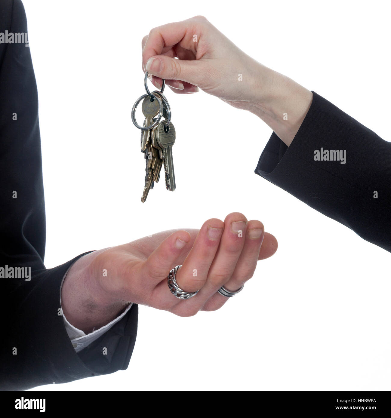 closeup of one hand with key ring hands over house keys to other hand ...