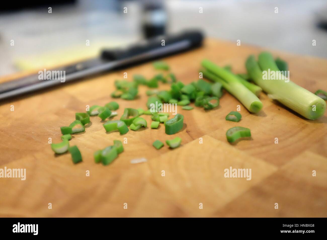 Spring onions on a chopping board with a knife Stock Photo - Alamy