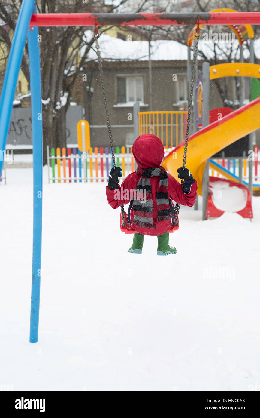 Boys swinging on a swing in snow Stock Photo - Alamy