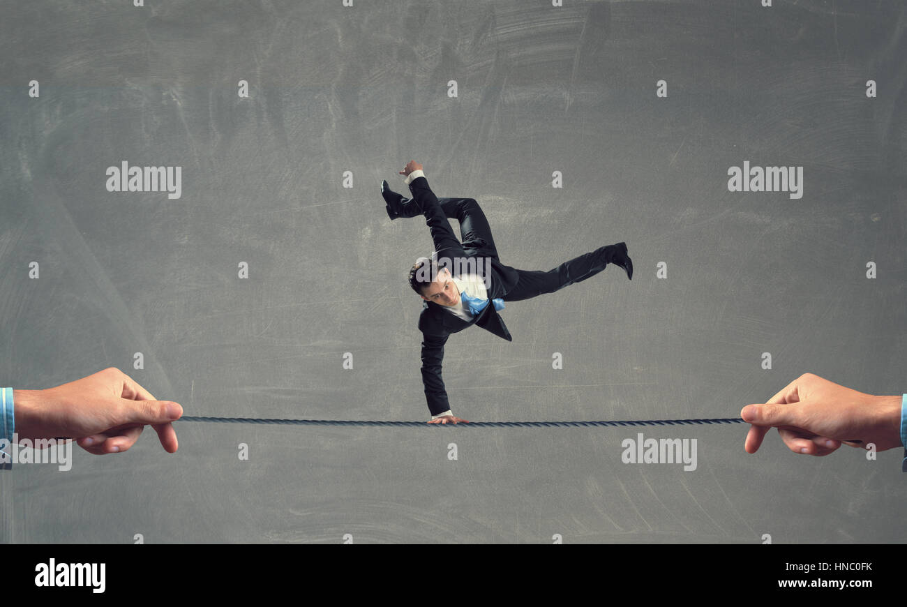 Young cheerful businessman doing handstand on strained rope Stock Photo ...