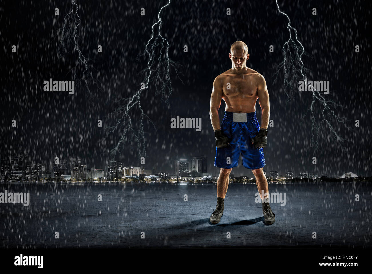 Strong fighter in shorts against dark sky background. Mixed media Stock ...