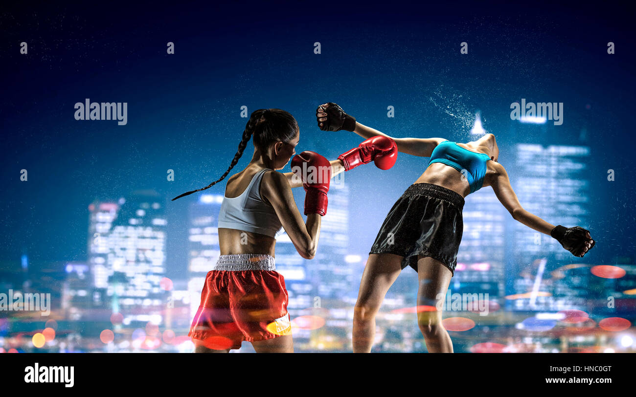 Two young pretty women boxing against night city background Stock Photo ...