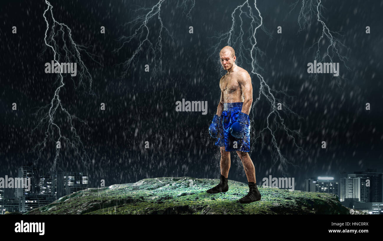 Strong fighter in shorts against dark sky background. Mixed media Stock ...