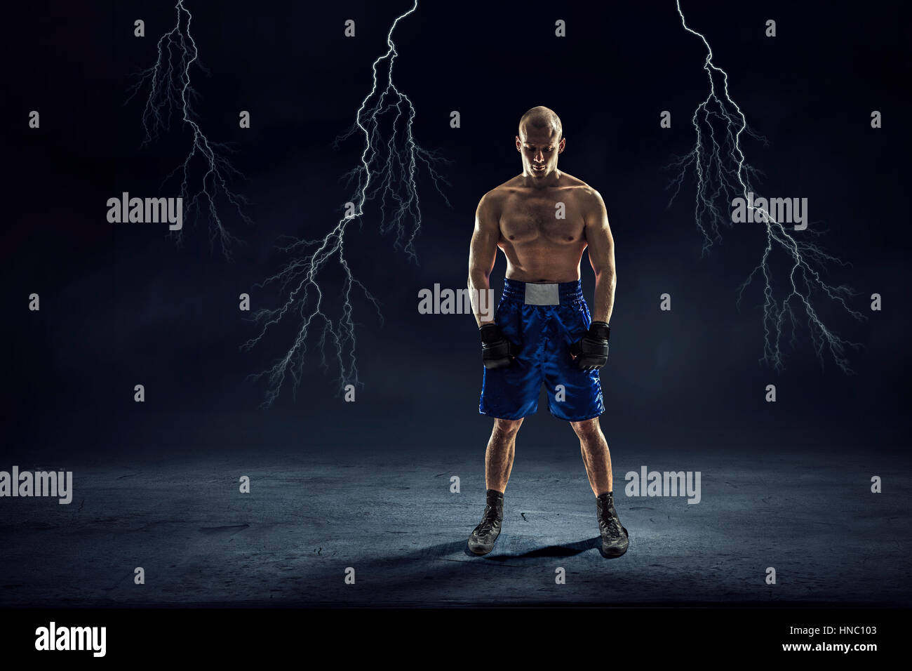 Strong fighter in shorts against dark sky background. Mixed media Stock ...