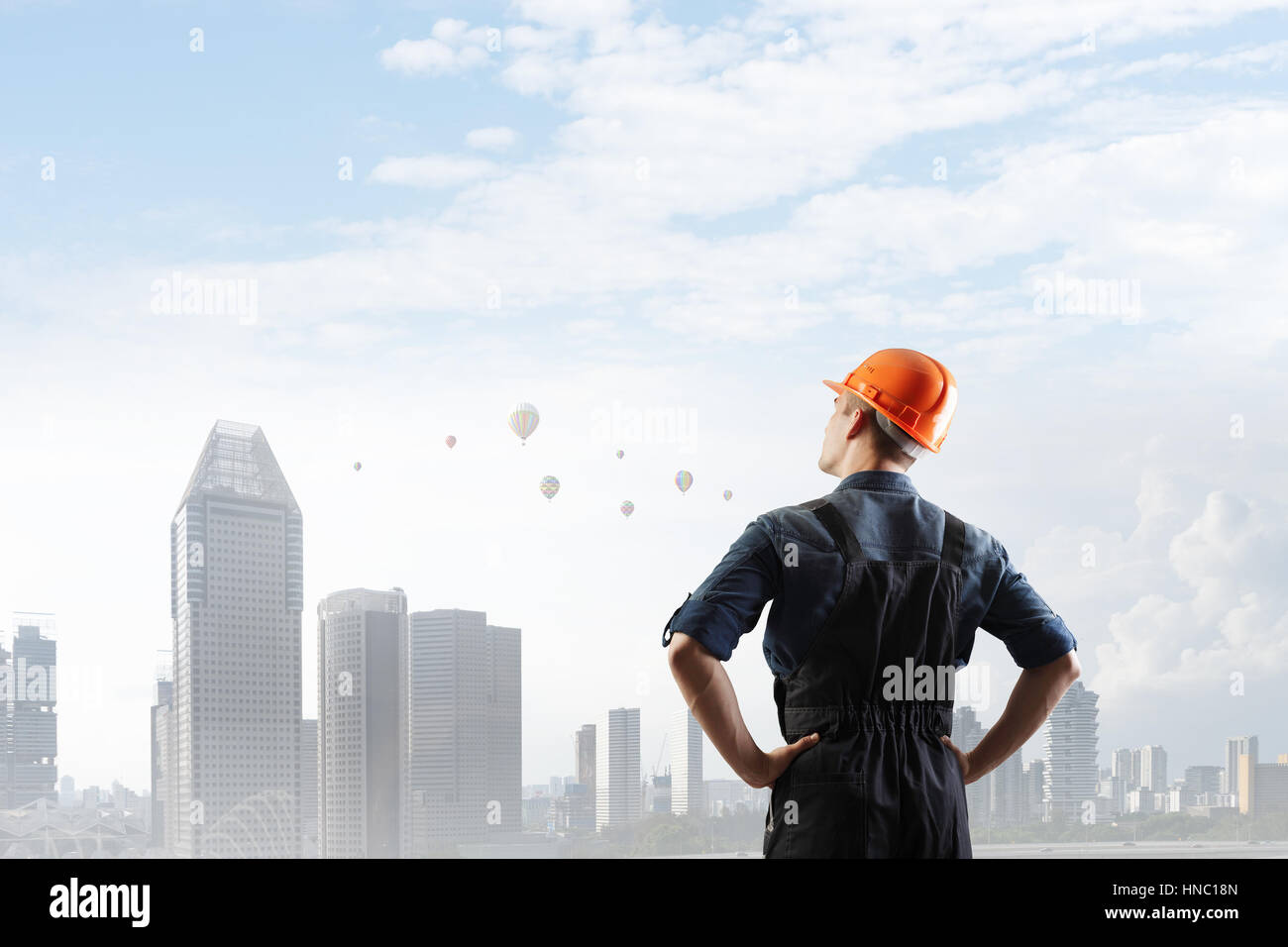 Back view of builder man looking at modern city Stock Photo - Alamy