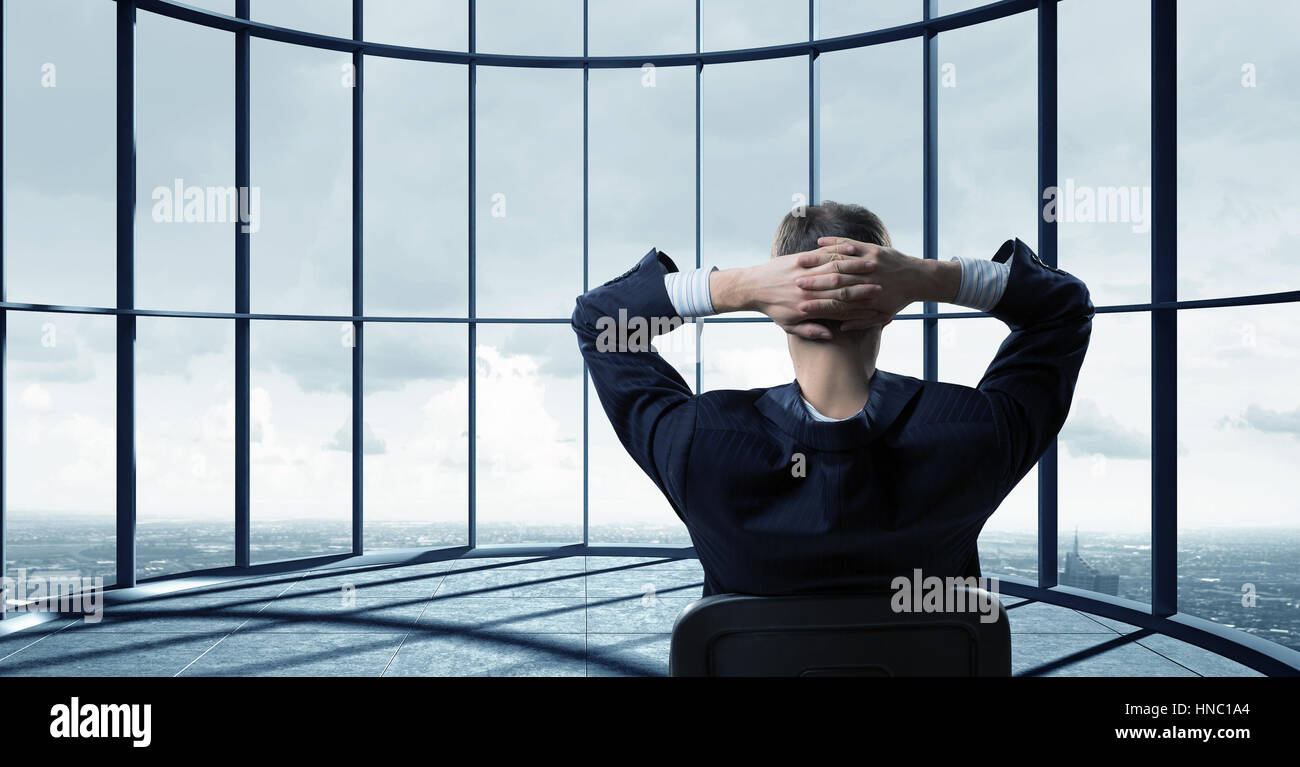 Back view of relaxed businessman sitting on chair with hands on nape ...