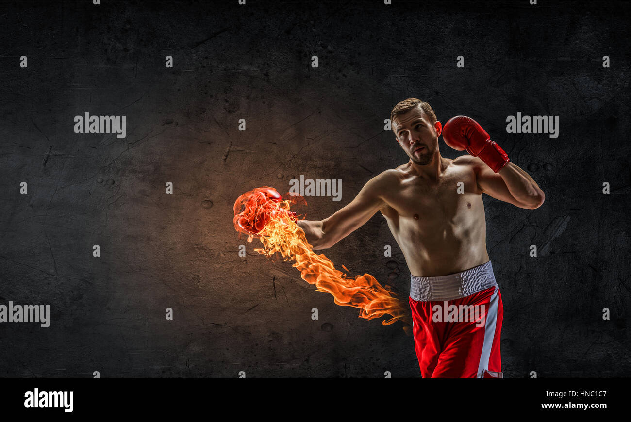 Strong fighter in shorts against dark wall background. Mixed media ...
