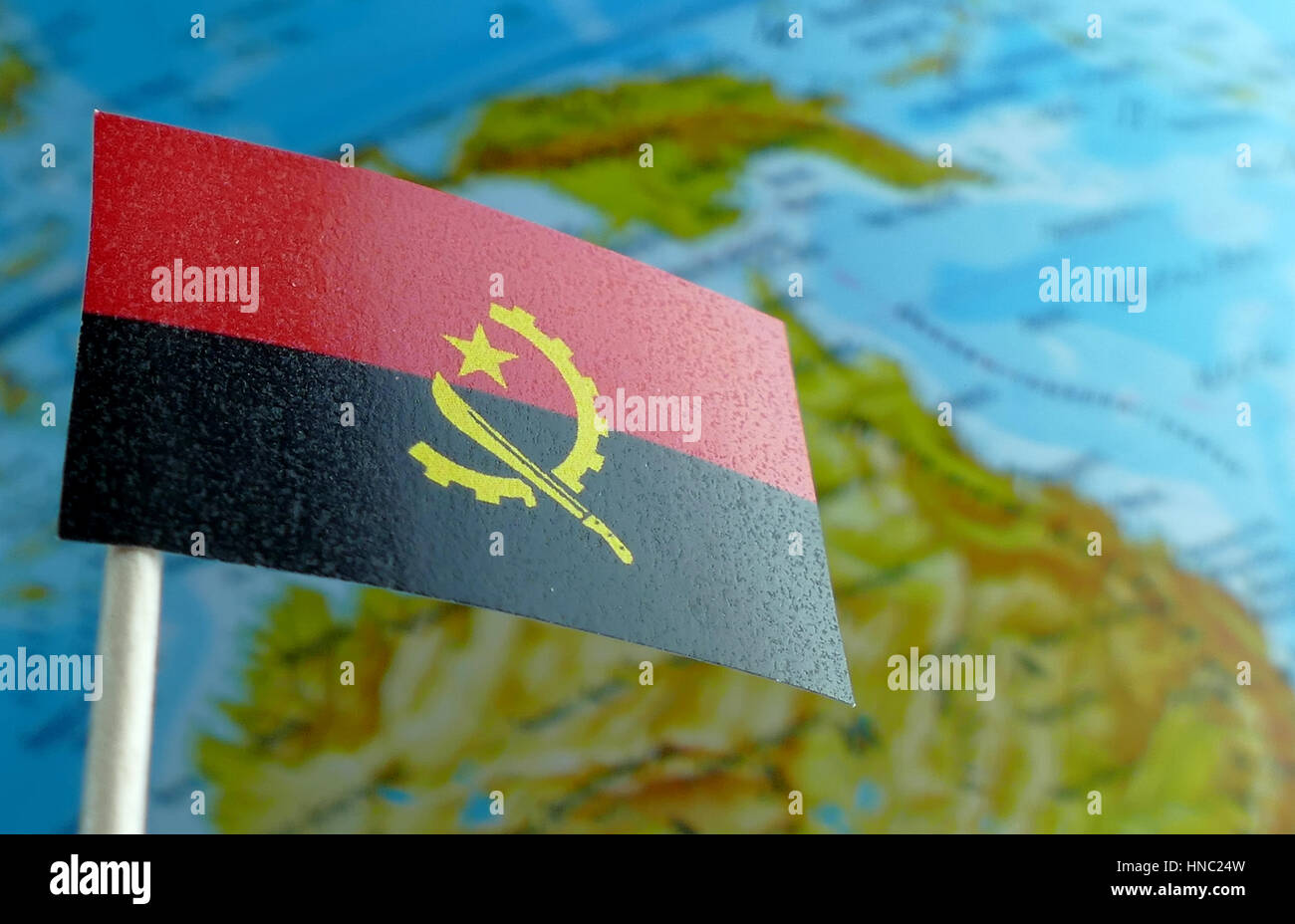 Angolan flag with a globe map as a background macro Stock Photo - Alamy