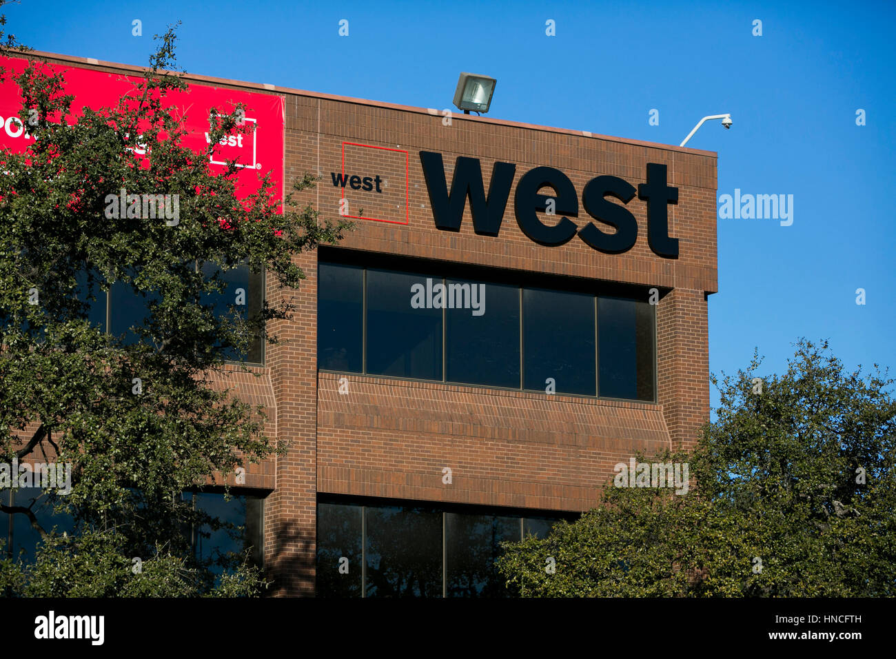 A logo sign outside of a facility occupied by the West Corporation in ...