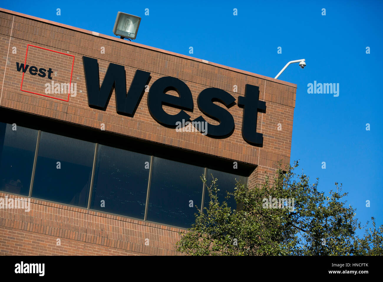 A logo sign outside of a facility occupied by the West Corporation in ...