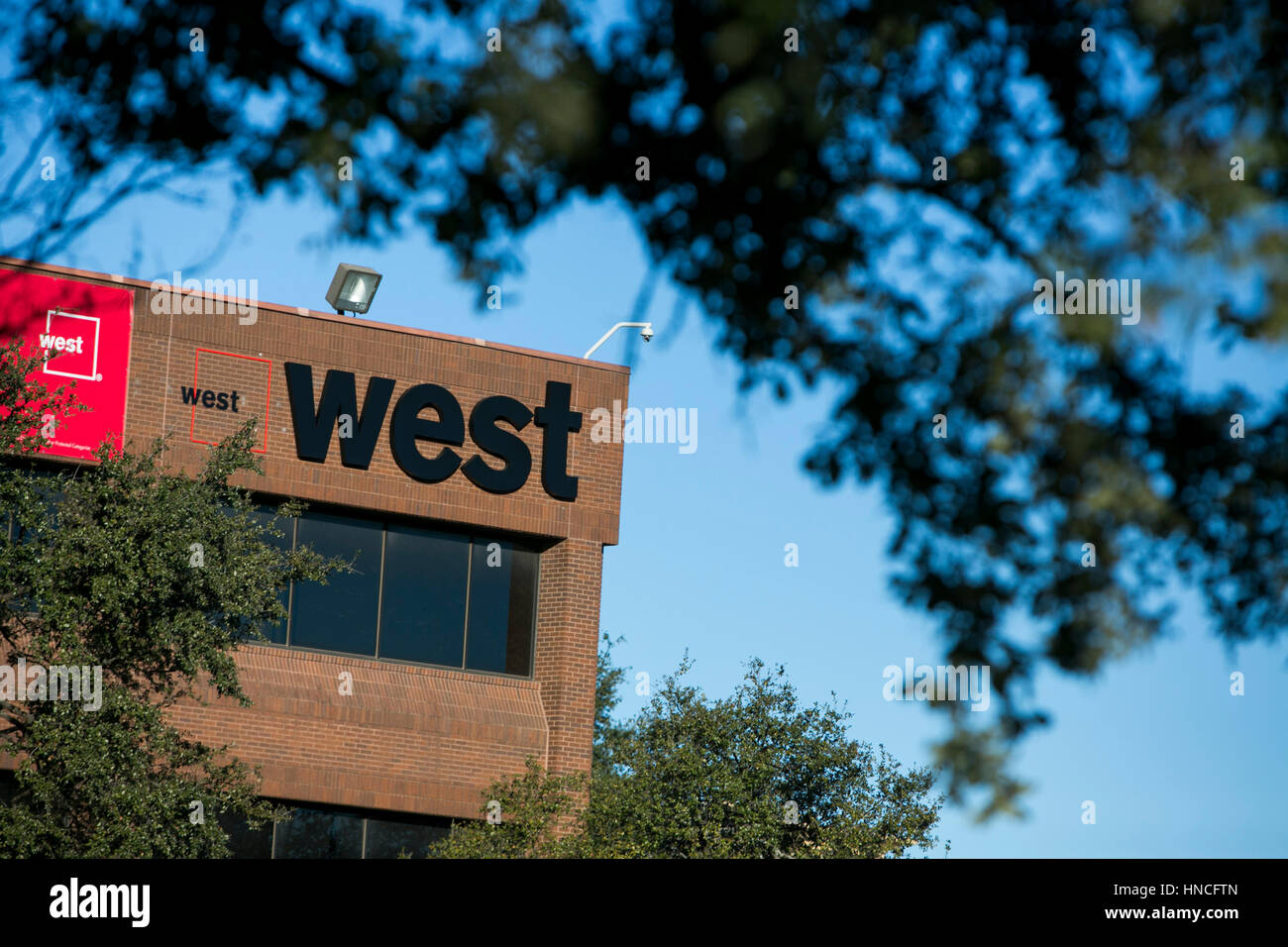 A logo sign outside of a facility occupied by the West Corporation in ...