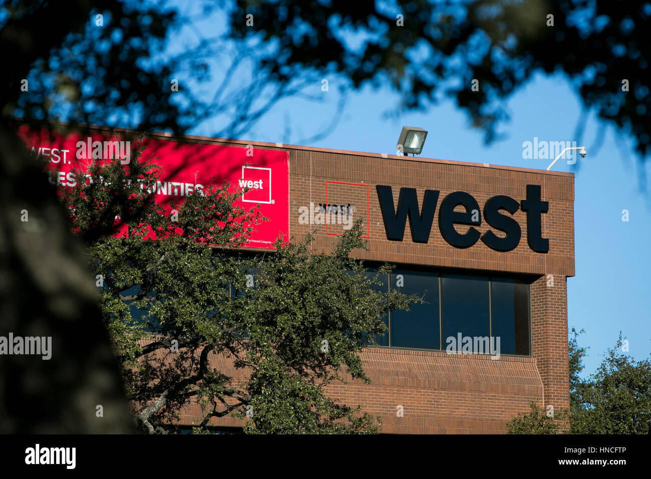 A logo sign outside of a facility occupied by the West Corporation in ...