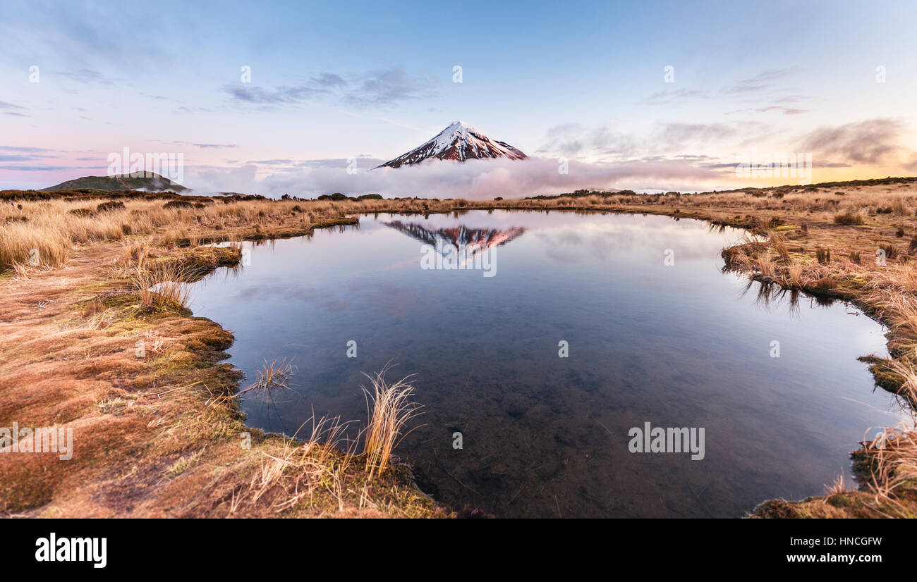Reflection in Pouakai Tarn lake, clouds around stratovolcano Mount ...