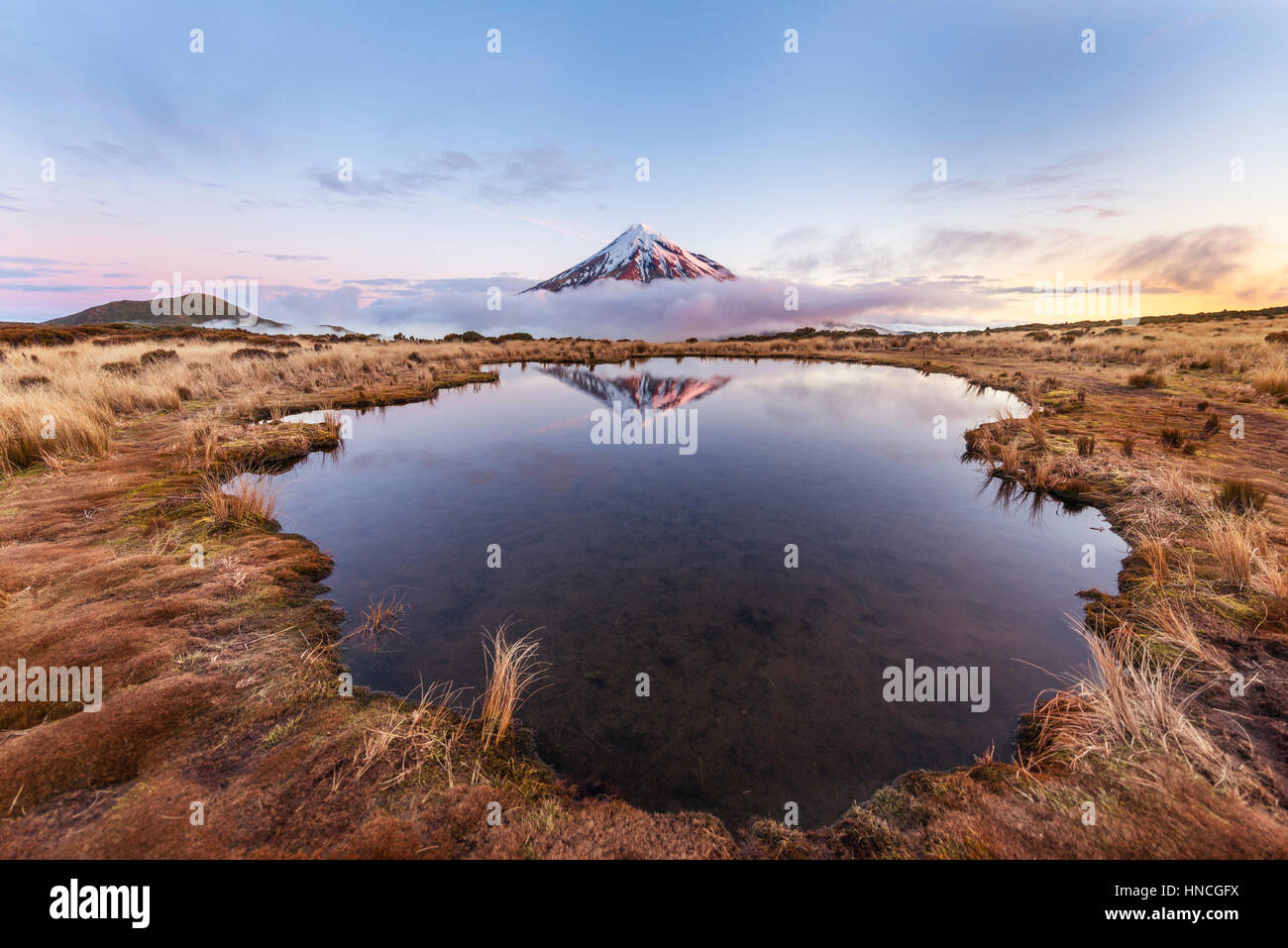Reflection in Pouakai Tarn lake, clouds around stratovolcano Mount ...