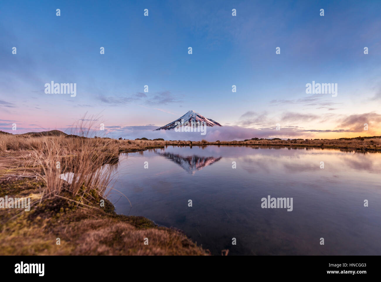 Reflection in Pouakai Tarn lake, clouds around stratovolcano Mount ...