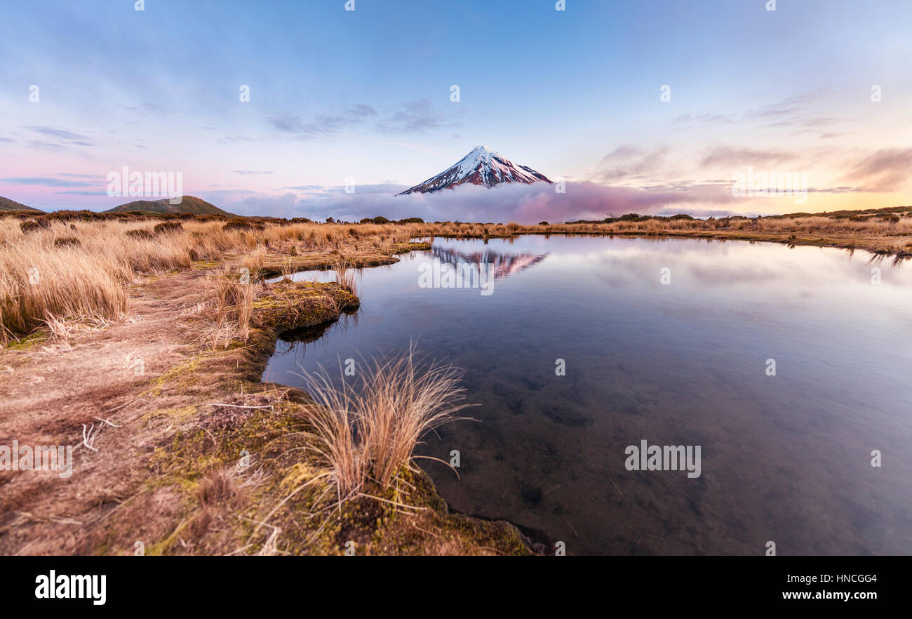 Reflection in Pouakai Tarn lake, clouds around stratovolcano Mount ...